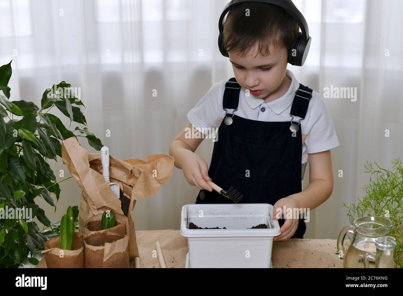 The boy, examines the gardening equipment, the small rake in his hand ...