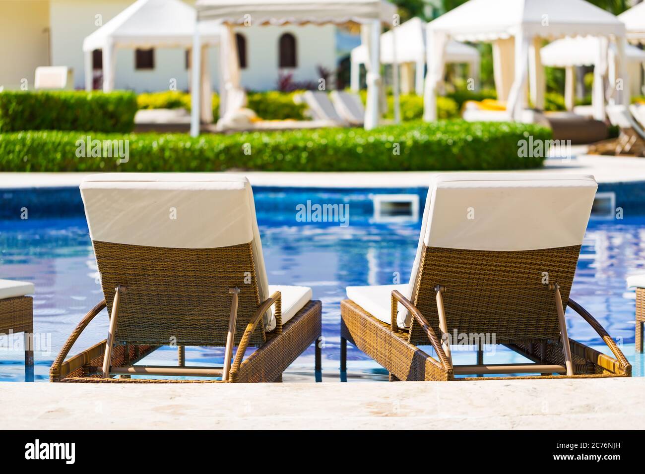 Resort swimming pool with deck chairs for relaxation Stock Photo - Alamy