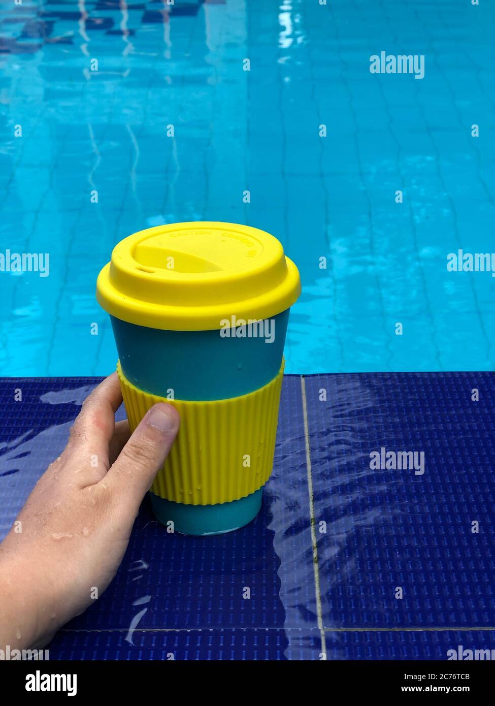 Woman enjoying coffee in a reusable bamboo mug at the swimming pool ...