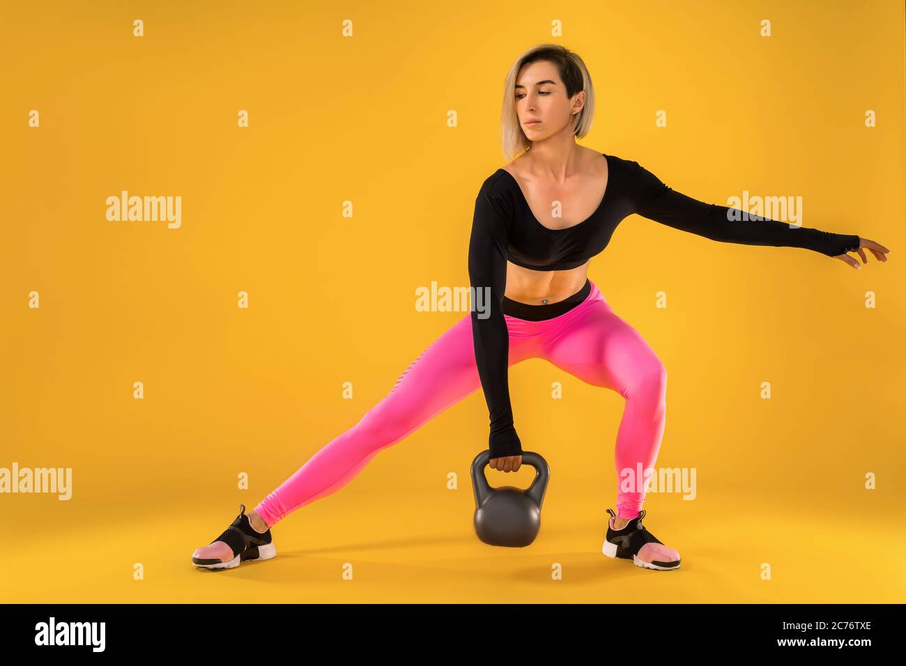Fitness woman in fashionable pink and black sportswear work out with ...