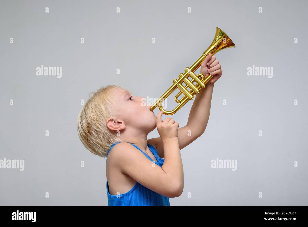 Little cute blond boy playing trumpet on light background Stock Photo ...