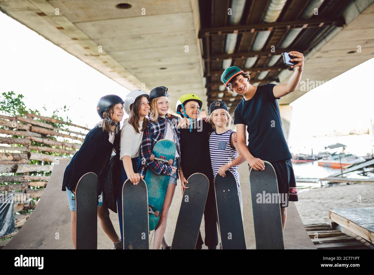Group of friends skateboarders taking selfie on phone in skate park ...