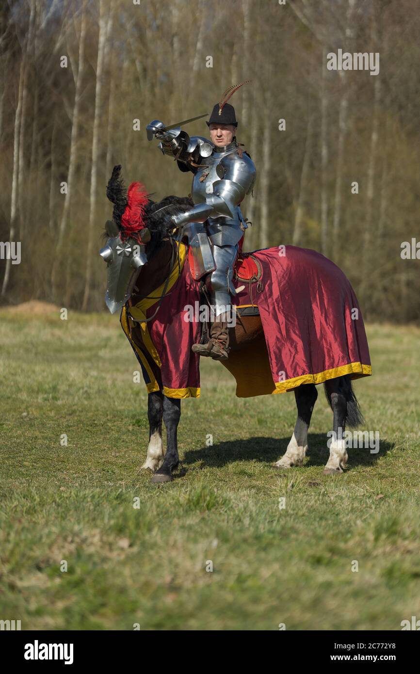 adult man in ancient knight armor rides across the field on a horse in ...