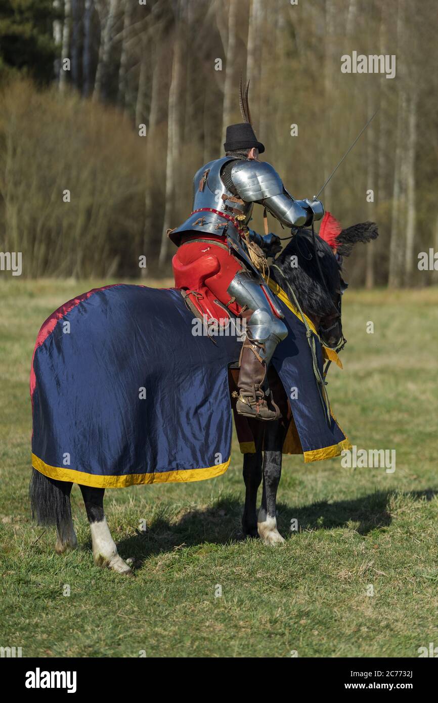 adult man in ancient knight armor rides across the field on a horse in ...