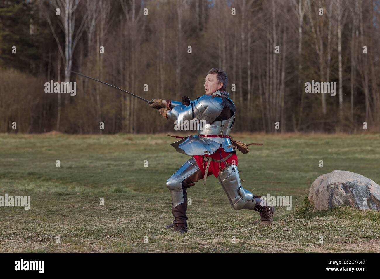 A walking knight in armor and holding a sword in his hands shows combat ...