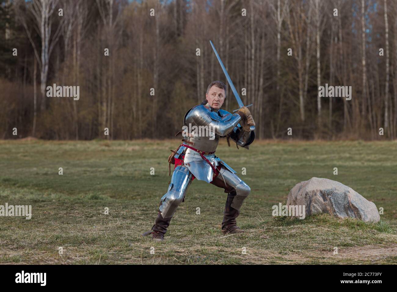 A walking knight in armor and holding a sword in his hands shows combat ...