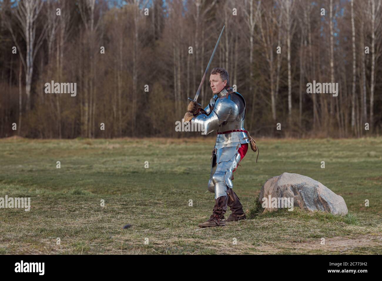 A walking knight in armor and holding a sword in his hands shows combat ...