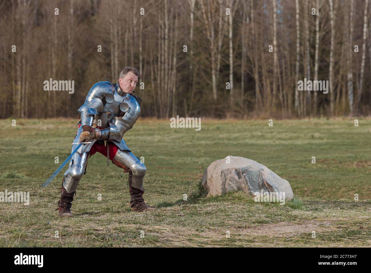 A walking knight in armor and holding a sword in his hands shows combat ...