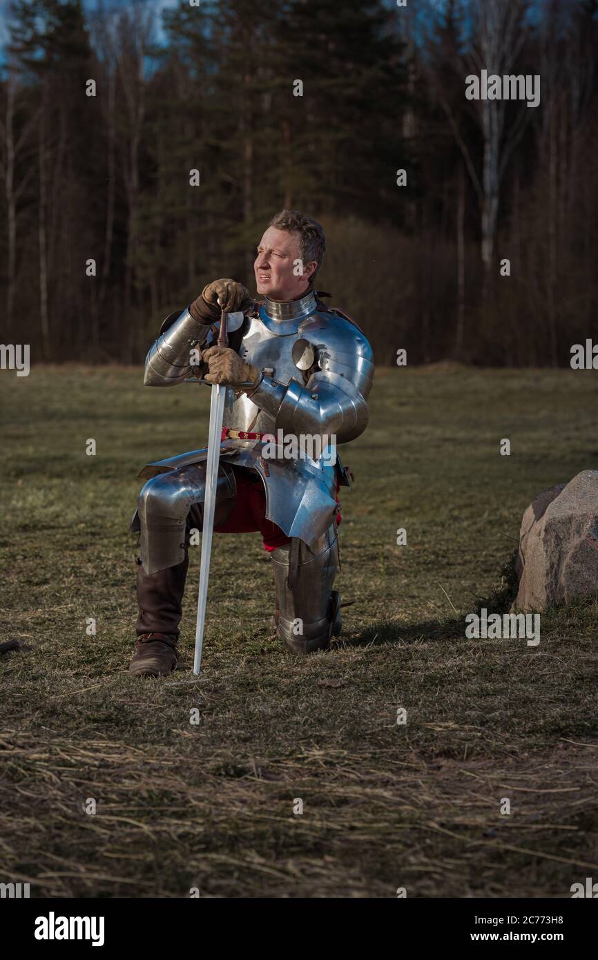 Infantryman knight in armor and with a sword resting on the battlefield ...