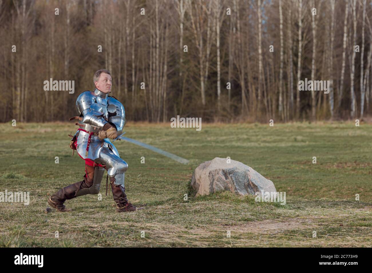 A walking knight in armor and holding a sword in his hands shows combat ...
