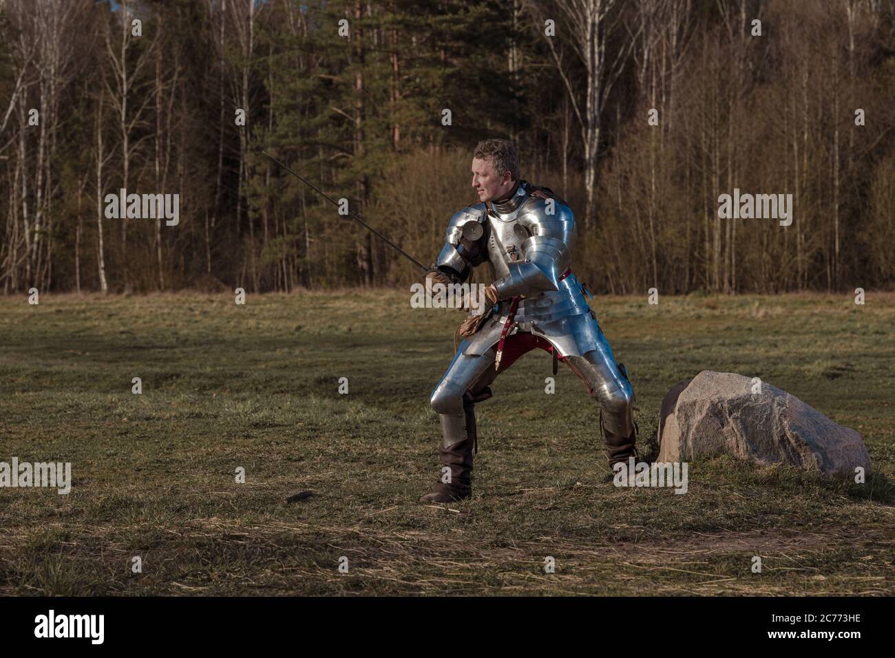 A walking knight in armor and holding a sword in his hands shows combat ...