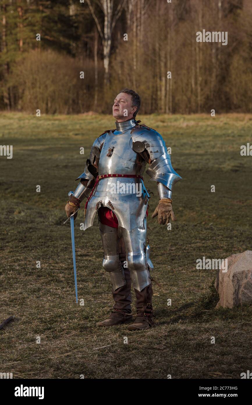 Infantryman knight in armor and with a sword resting on the battlefield ...
