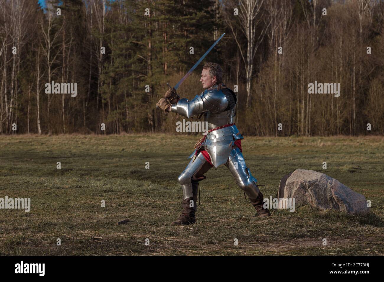 A walking knight in armor and holding a sword in his hands shows combat ...