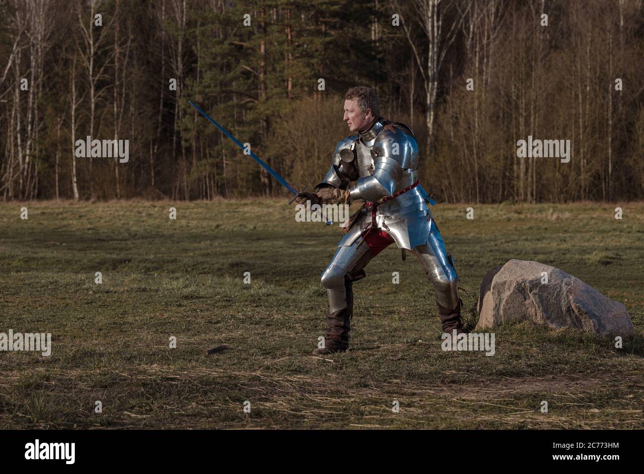 A walking knight in armor and holding a sword in his hands shows combat ...
