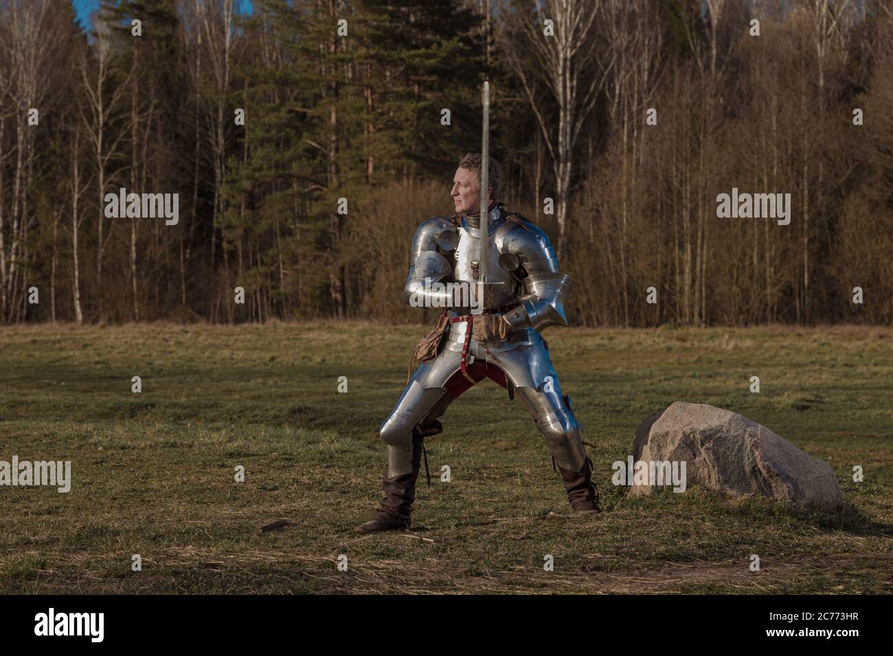 A walking knight in armor and holding a sword in his hands shows combat ...