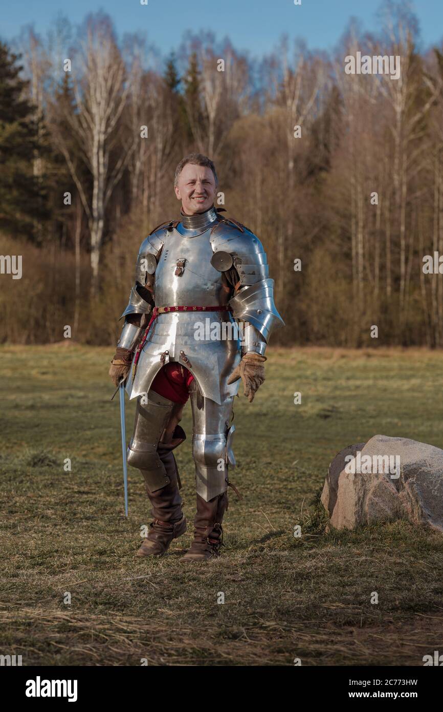 A walking knight in armor and holding a sword in his hands shows combat ...
