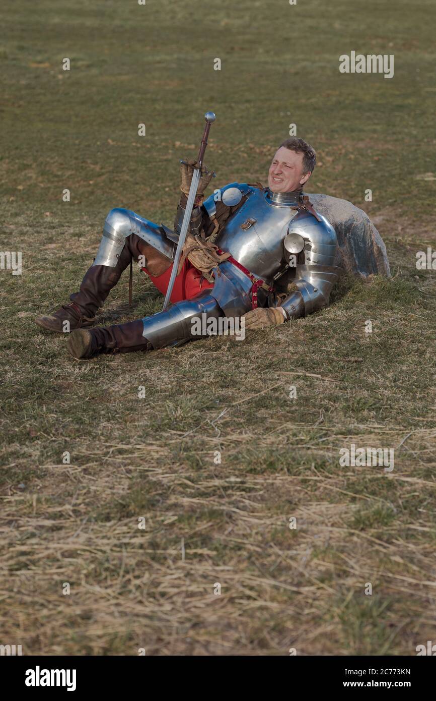 Infantryman knight in armor and with a sword resting on the battlefield ...