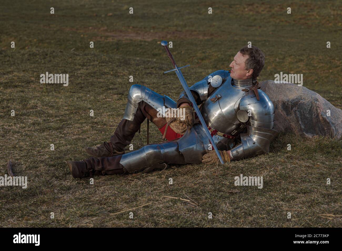 Infantryman knight in armor and with a sword resting on the battlefield ...