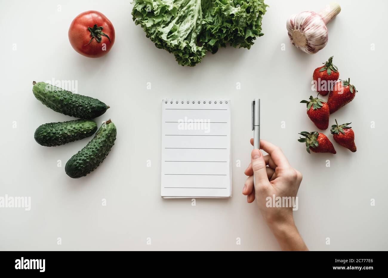 Woman makes notes in a notebook, food shopping list or writing recipes ...