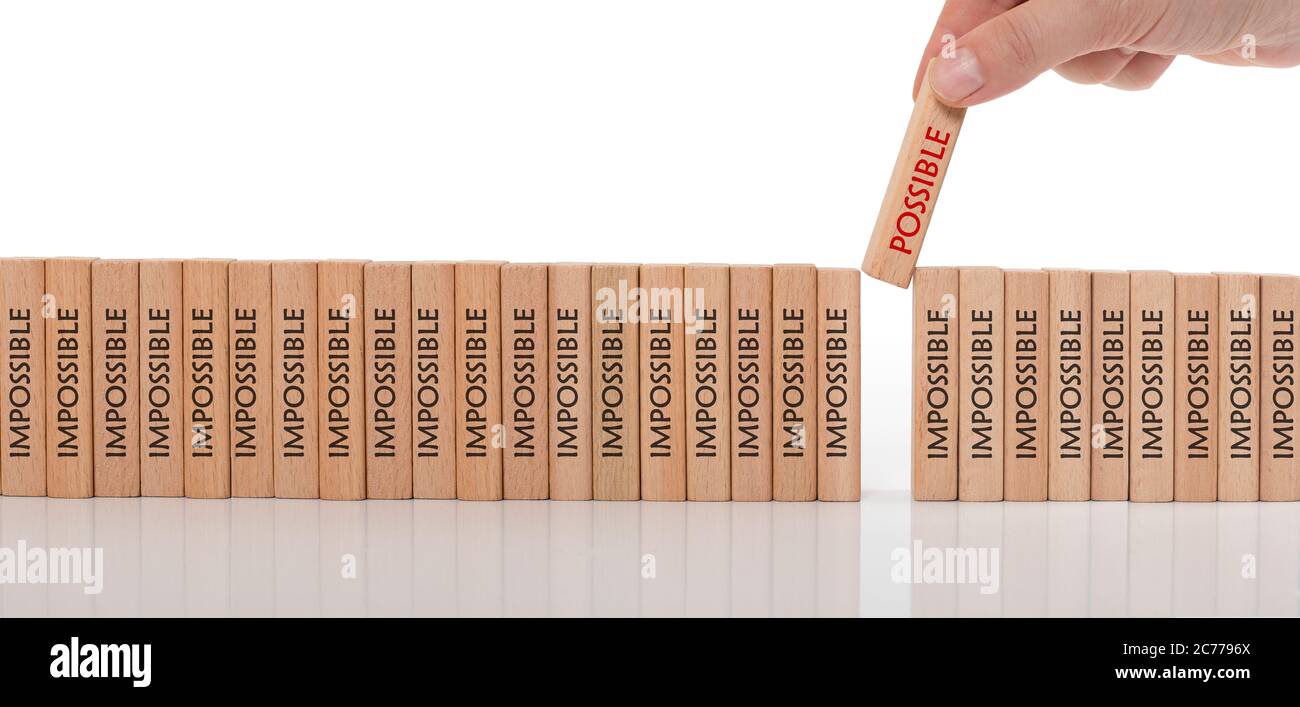 impossible to possible concept. hand chooses wooden cube labeled ...