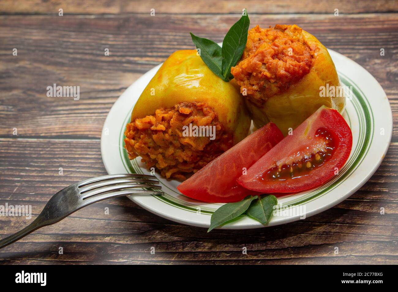 Hot stuffed peppers on a plate with a fork on a wooden background Stock ...