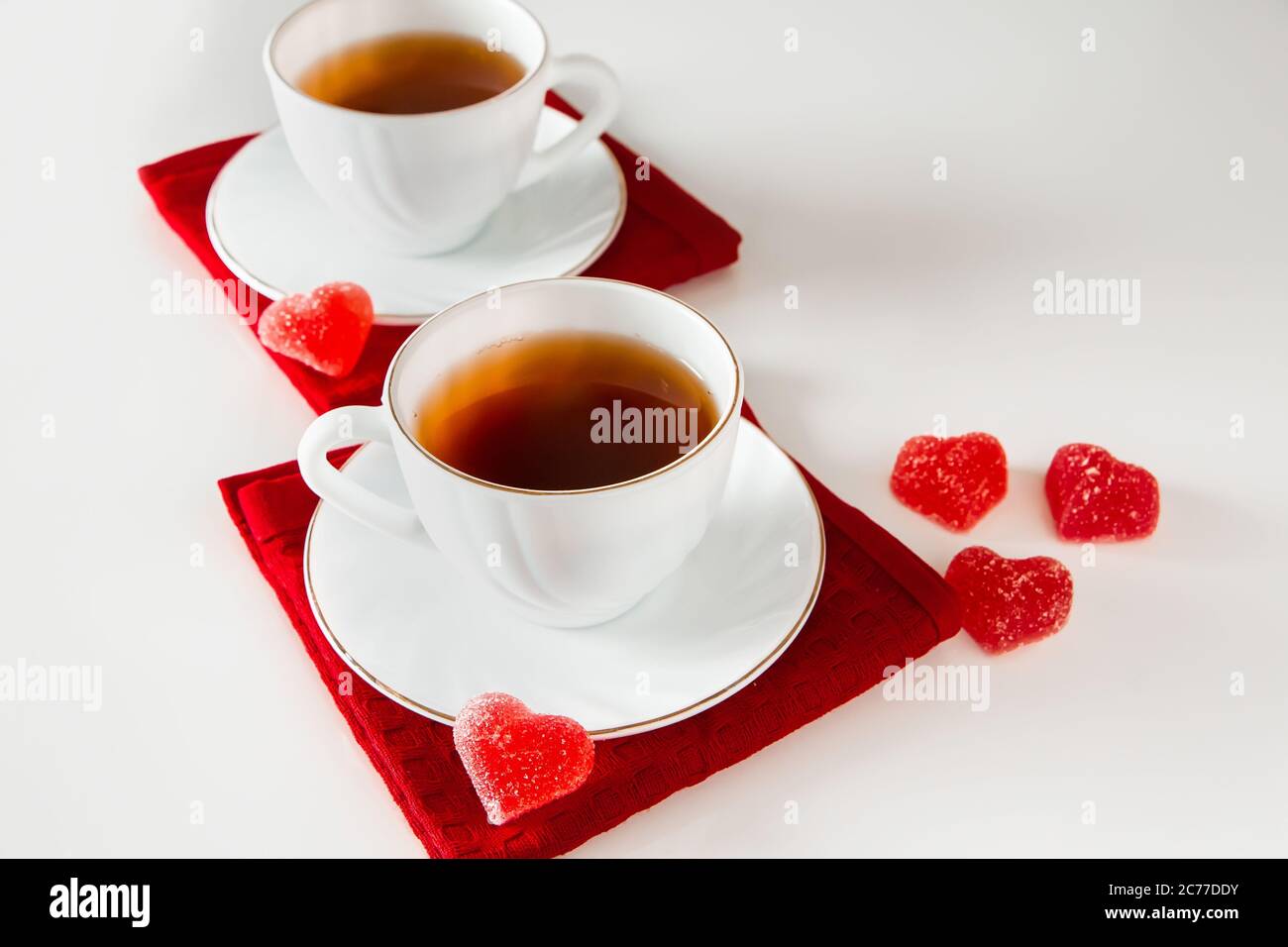 Two white cups of tea on a white background. Heart shaped marmalade ...