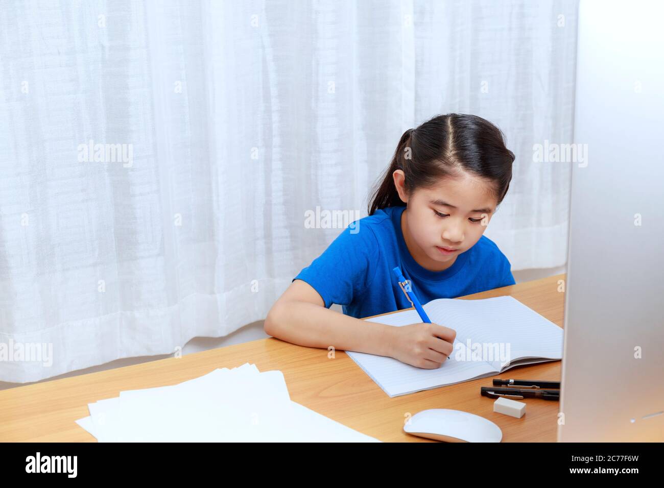 Asian little girl is studying online via the internet sitting and ...
