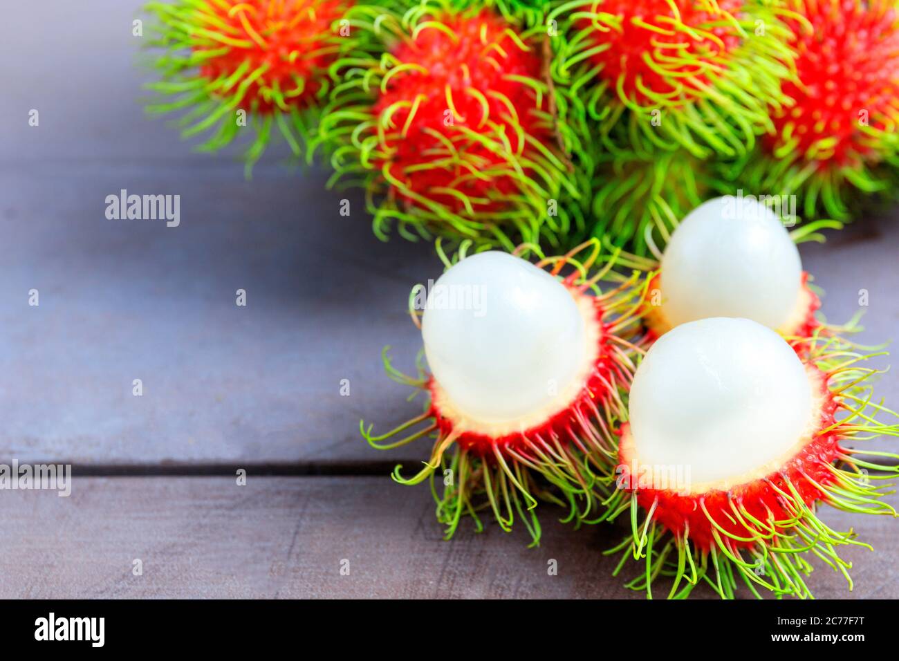 Fresh rambutan peeled on wood table with bunch of fresh ripe rambutan ...