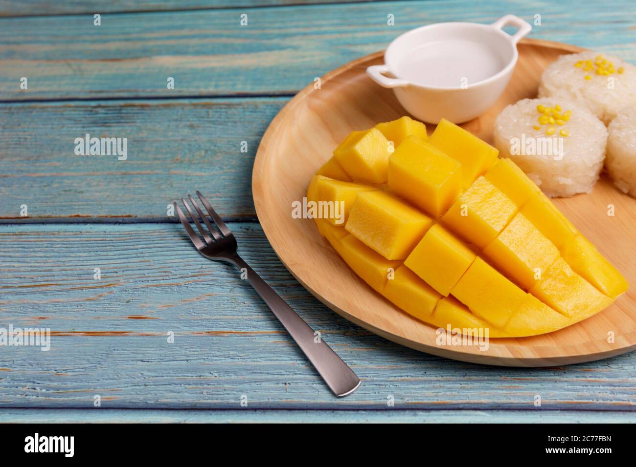 Yellow half mango with small fork. Mango fruit cubes on the Blue wooden ...