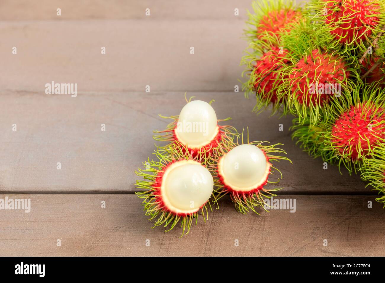 Fresh rambutan peeled on wood table with bunch of fresh ripe rambutan ...