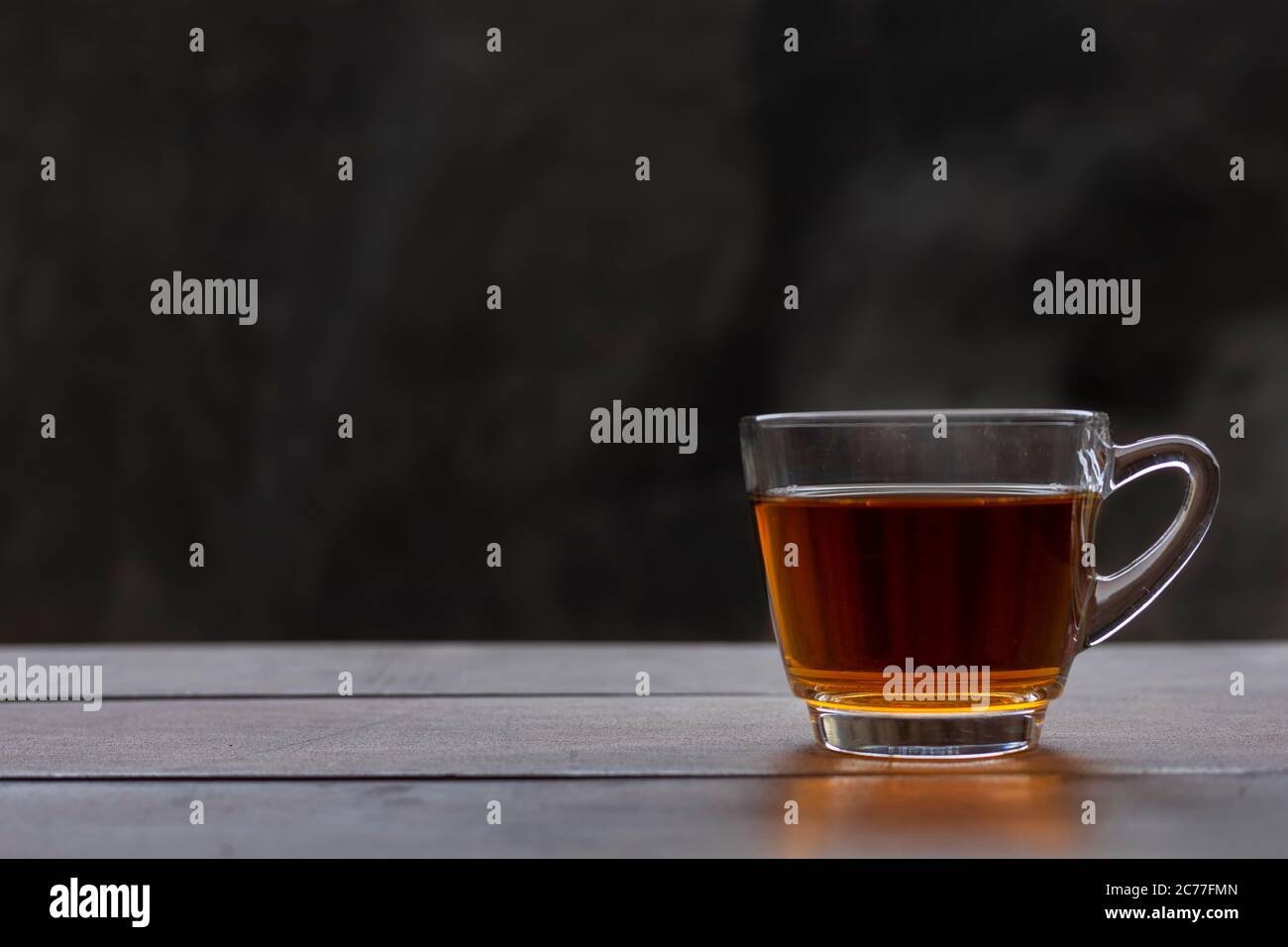 Close up hot tea cup on wood table . hot tea in handle glass with copy ...