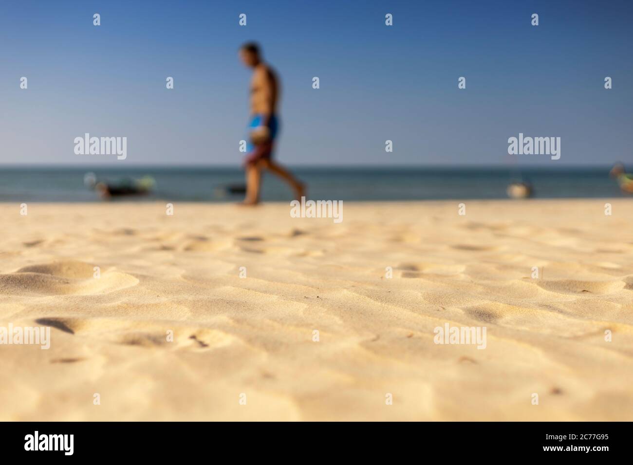 Holiday concept. Clear sand with blur guy, sea and clear sky background ...