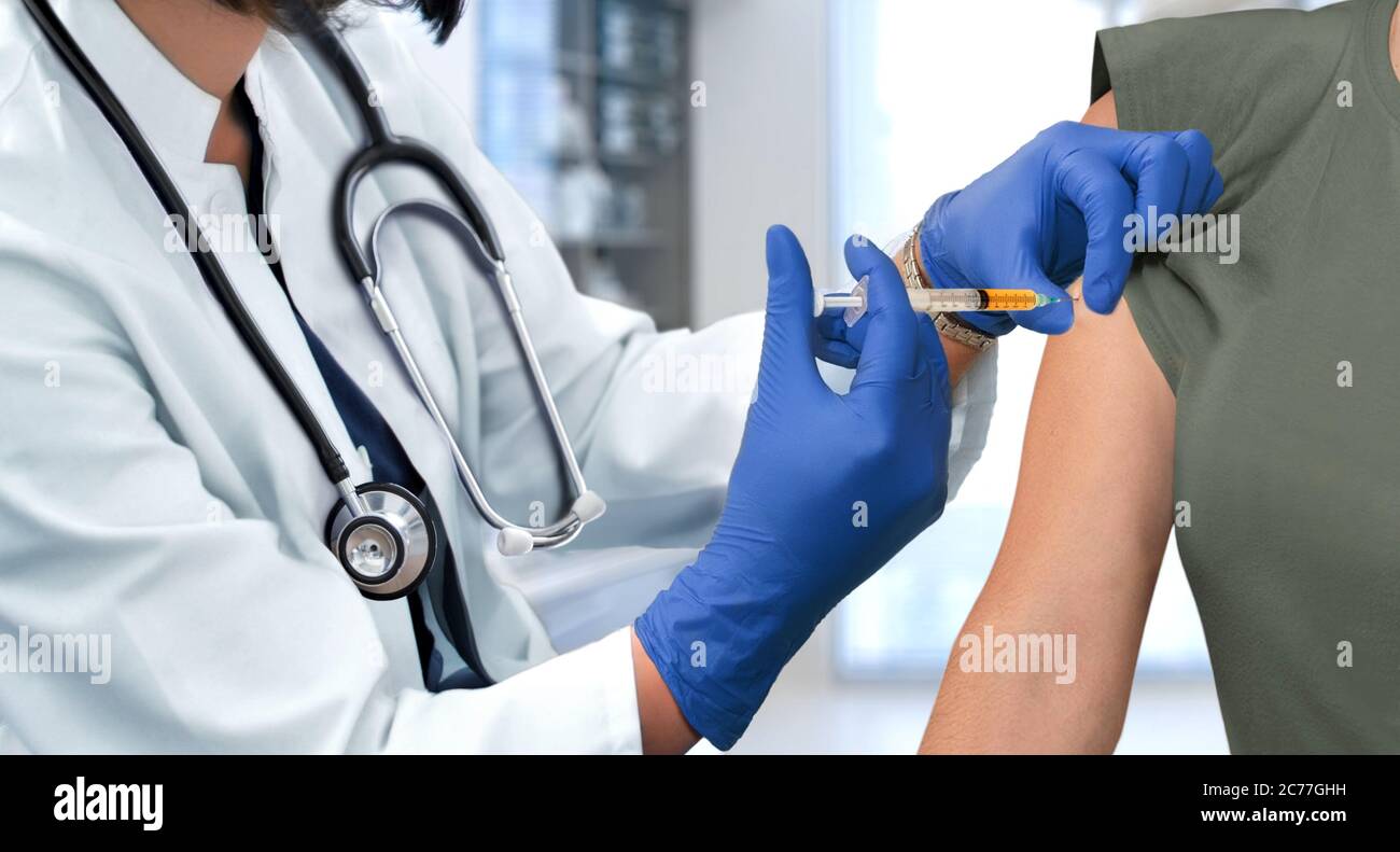 Doctor injecting patient's arm in the hospital clinic using syringe ...