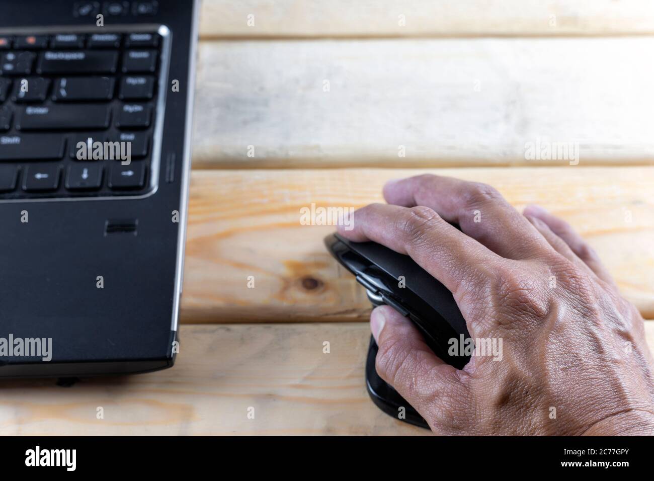 Hand hold mouse control laptop on wood table. With copy space for text ...
