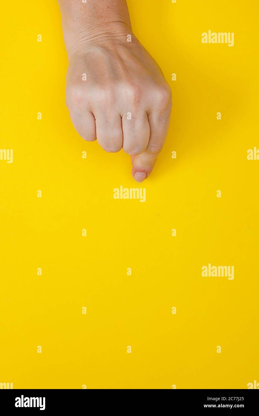 Hand with clenched fingers in a pinch on a yellow background Stock ...