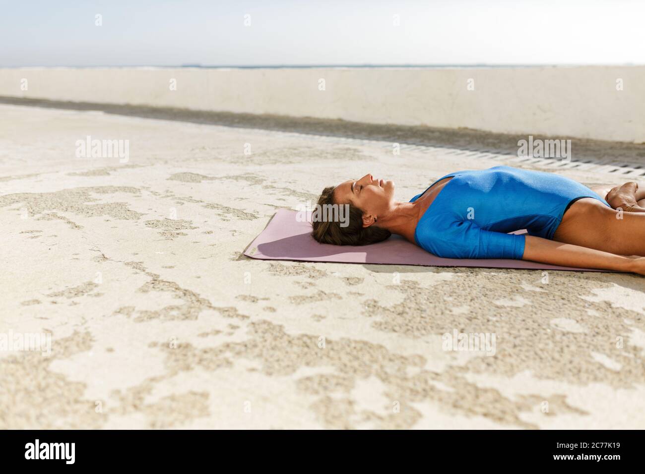 Woman with dark sort hair lying on yoga mat and training yoga poses ...