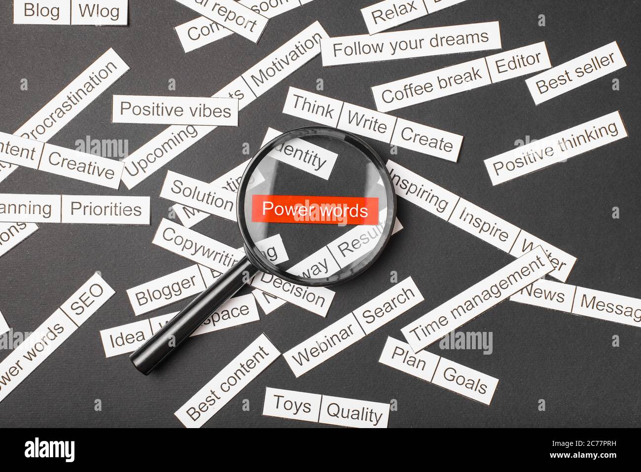 Magnifier glass over the red inscription power words cut out of paper ...