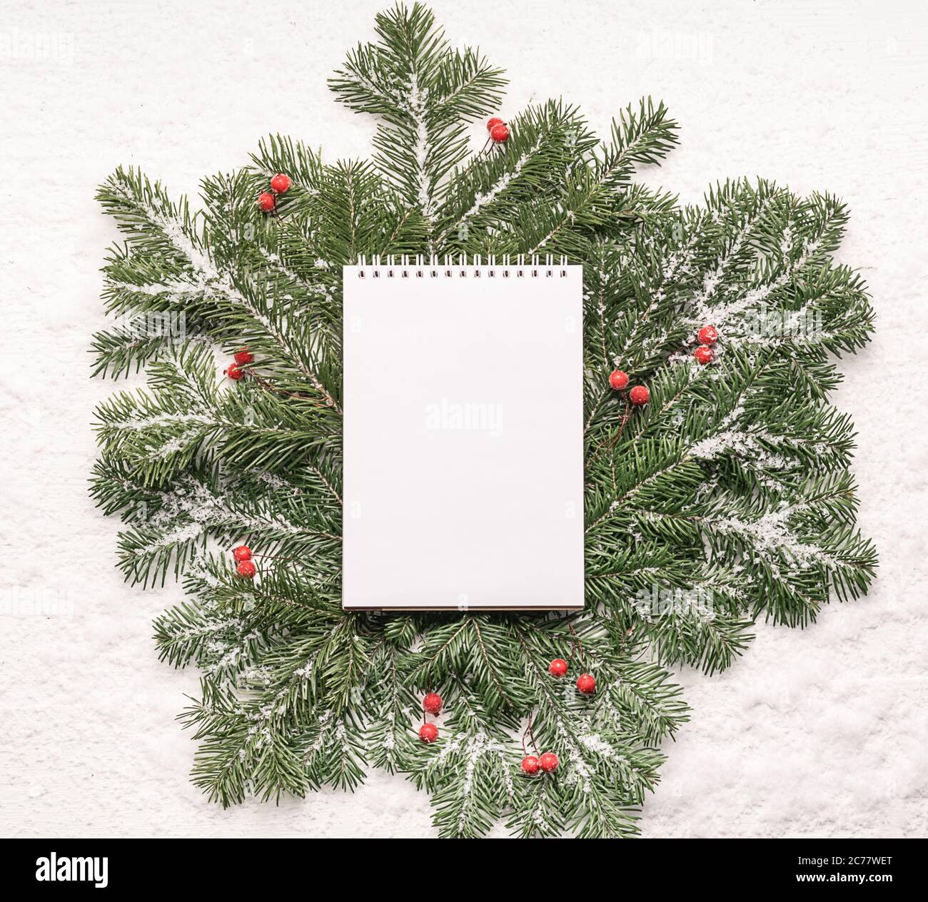 Fluffy green branches of spruce blank paper notepad on a white wooden ...