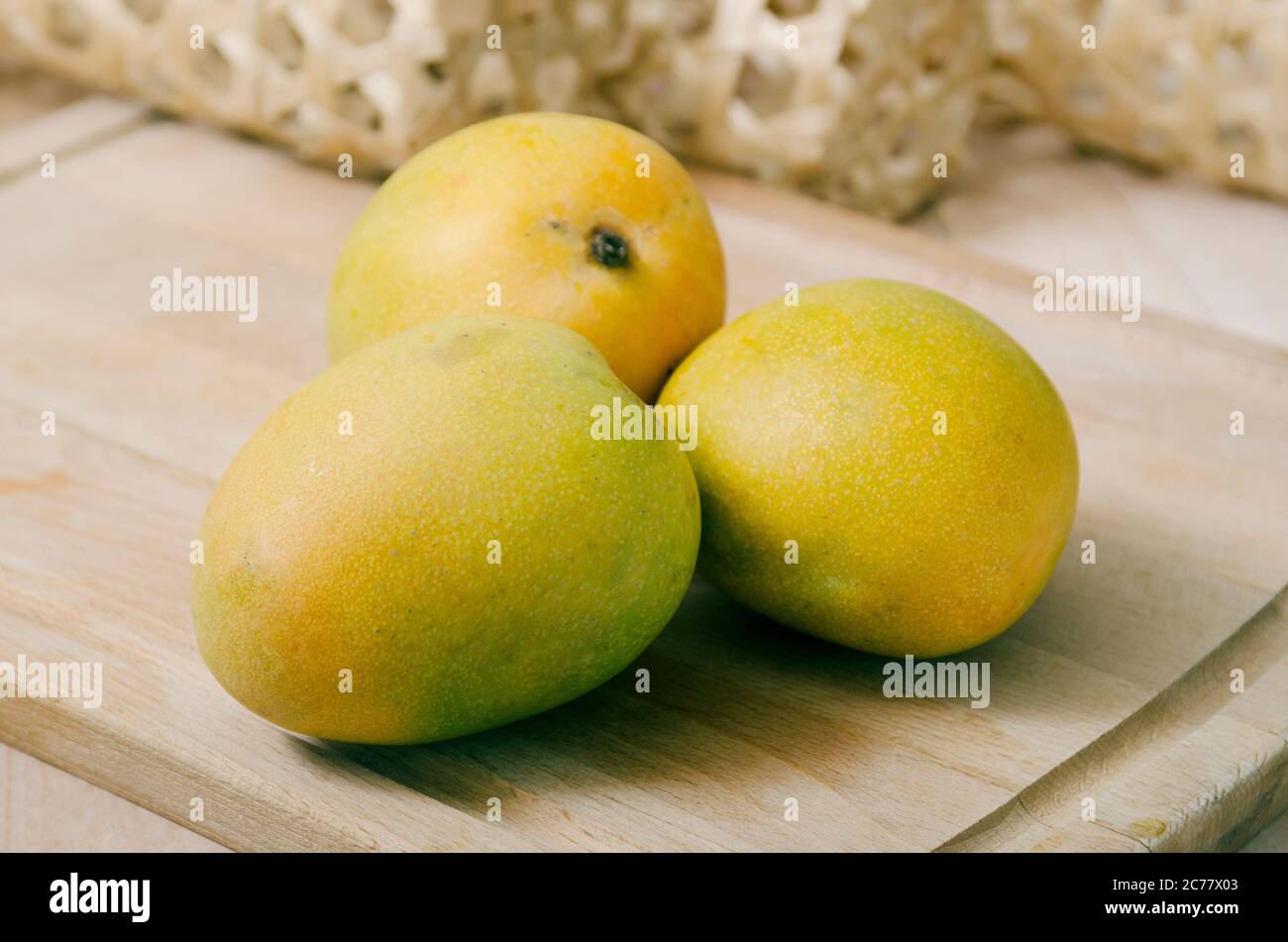 three mango with wooden background and rattan basket Stock Photo - Alamy