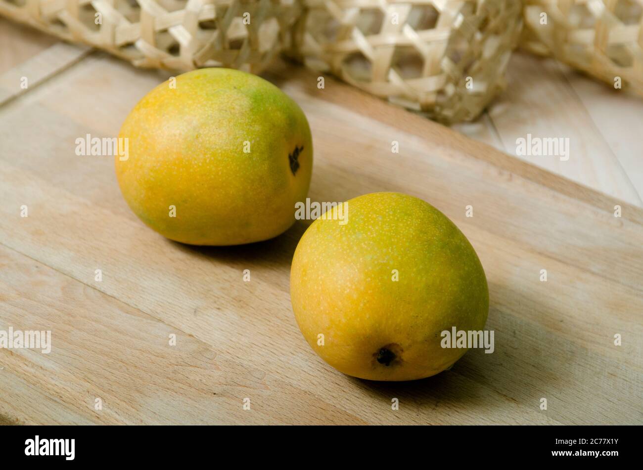 three mango with wooden background and rattan basket Stock Photo - Alamy