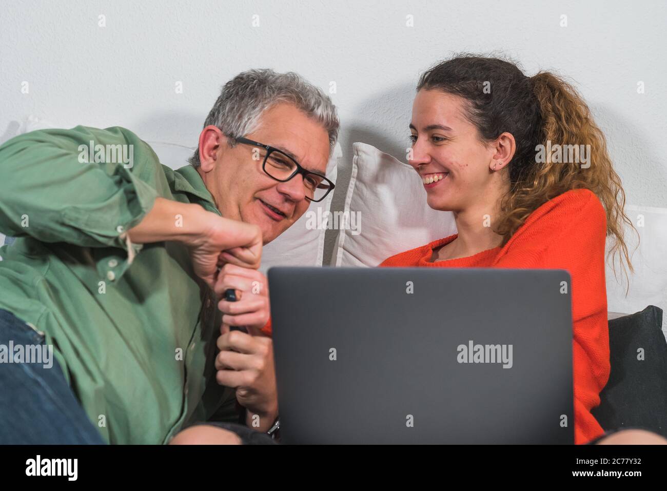 Father and daughter using a laptop. Teenager teaches father how to use ...