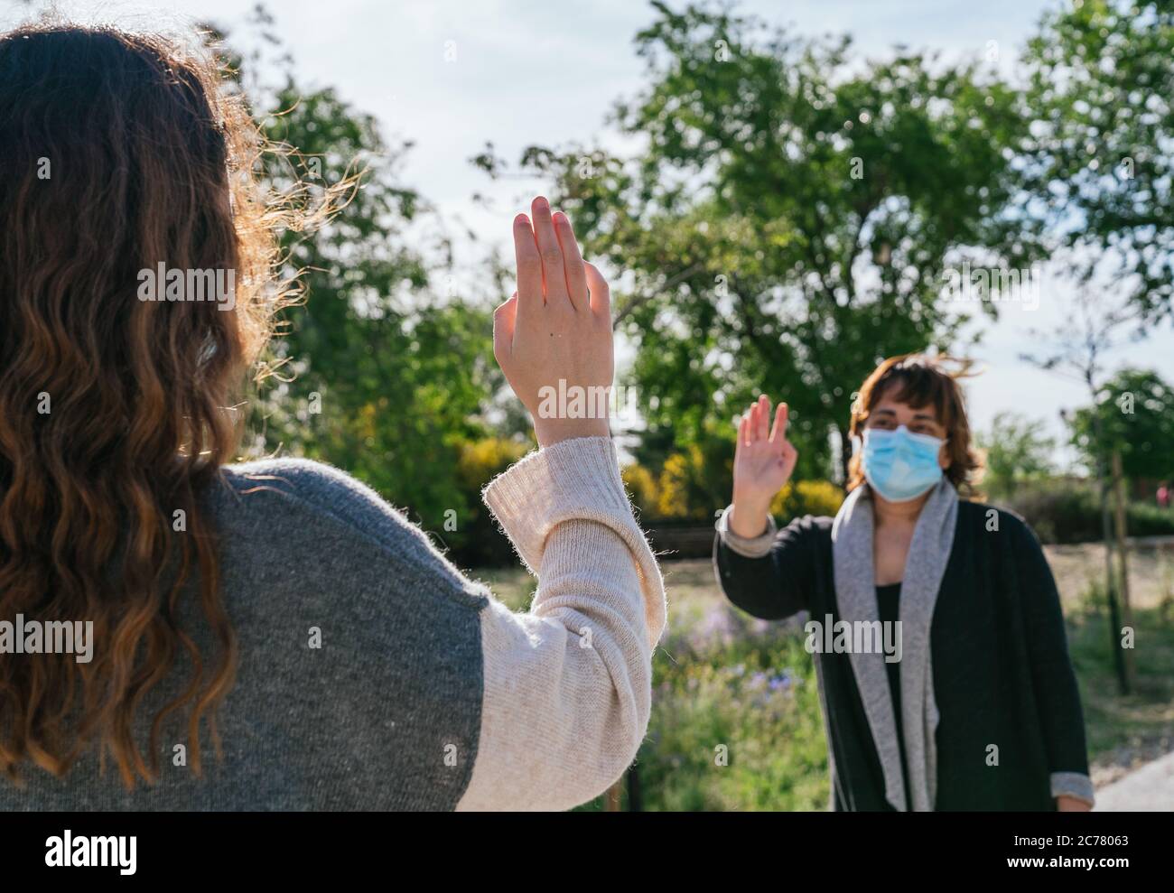 Social distance. Two women greet each other while keeping a safe ...