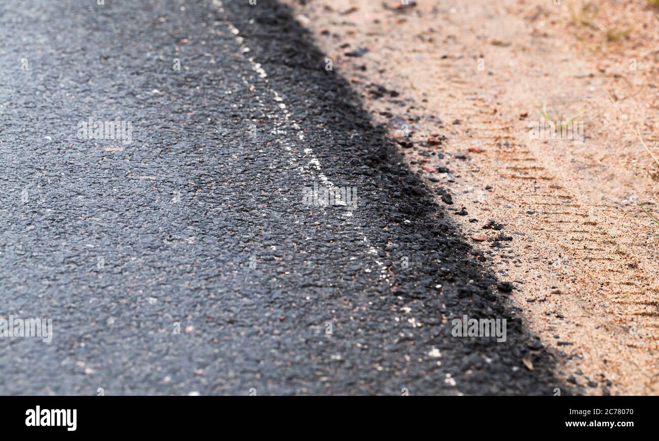 New asphalt road edge and sandy roadside. Abstract transportation ...