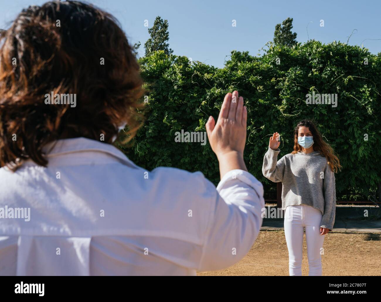 Social distance. Two neighbors walk through a park and greet each other ...