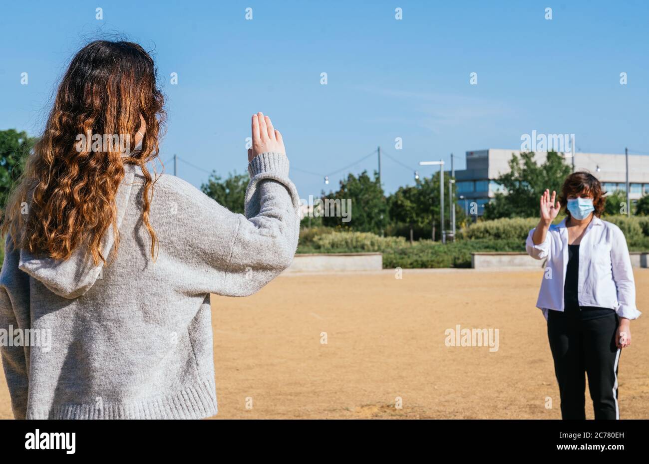 Social distance. Two neighbors walk through a park and greet each other ...