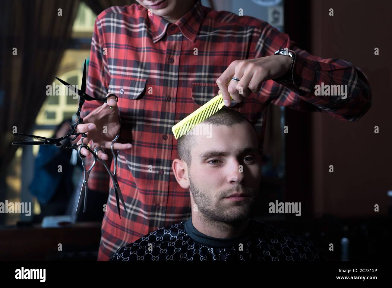 hairdresser a young guy with many scissors in his hand, cuts with a ...