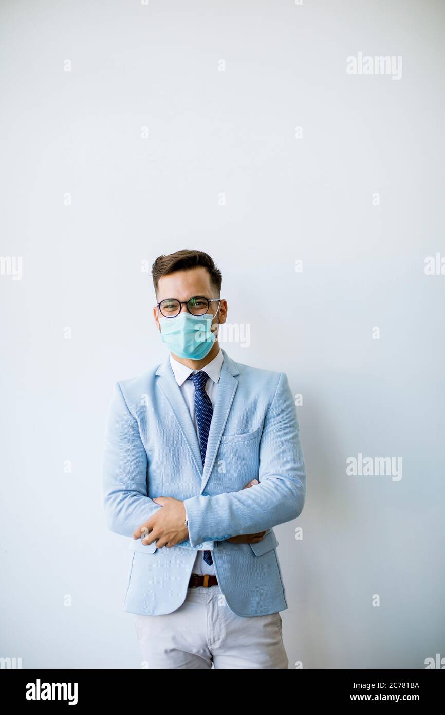 Young and stylish business man with protective face mask stands by the ...