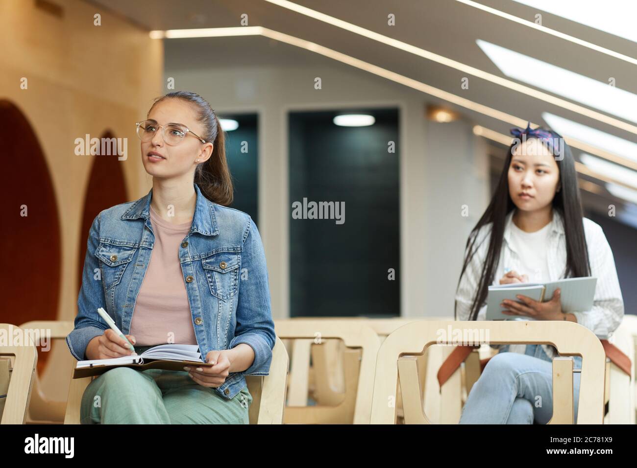 Pensive multi-ethnic student girls in casual outfits sitting with ...
