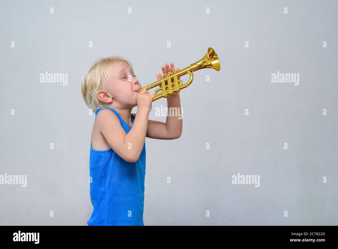 Little cute blond boy playing trumpet on light background Stock Photo ...