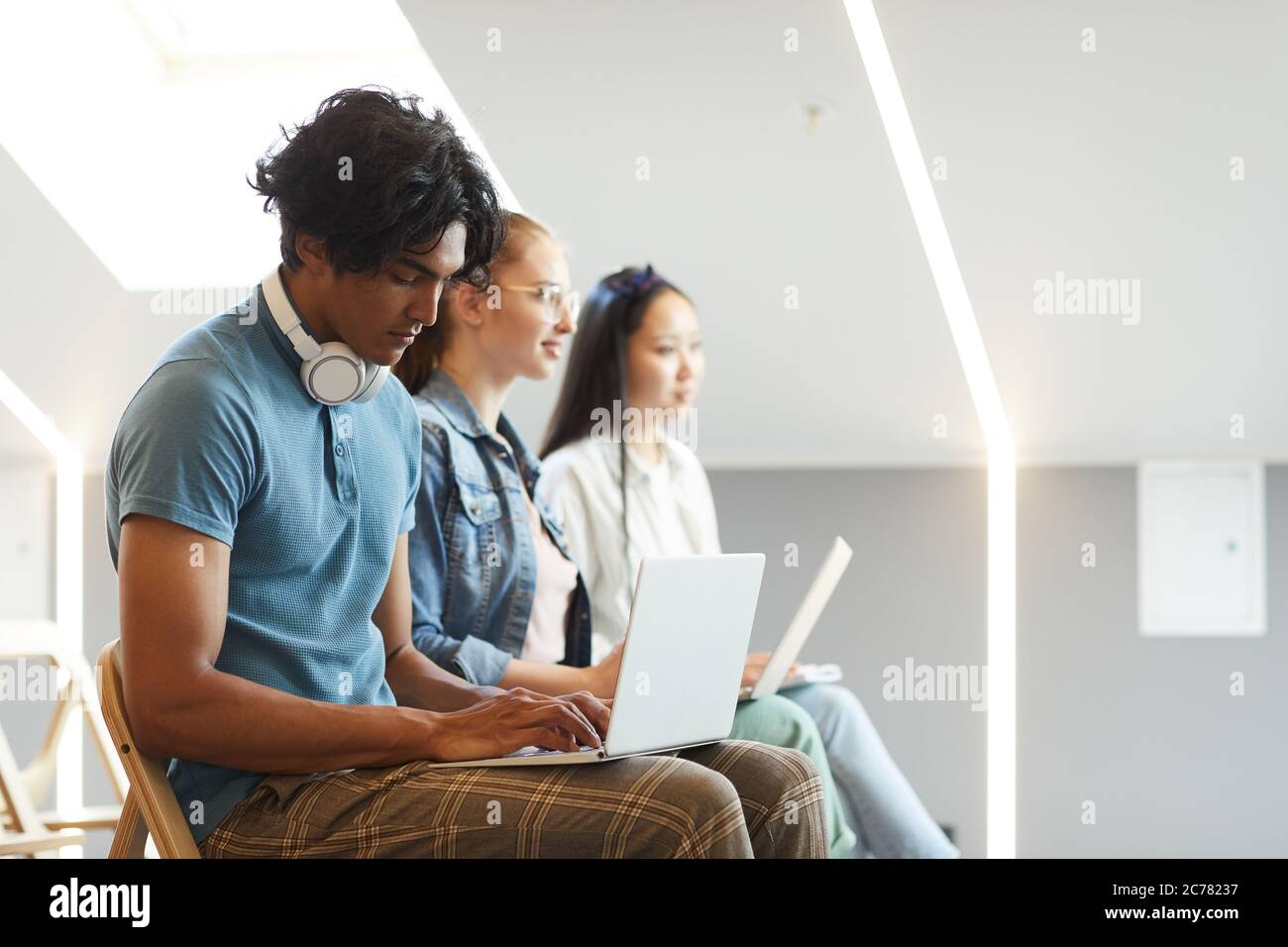 Side view of concentrated multi-ethnic students sitting in row and ...